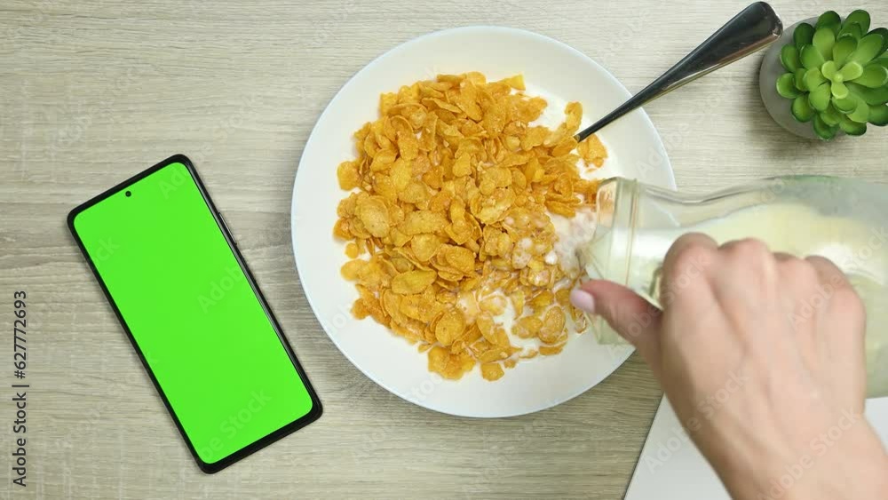 Woman breakfast cereal with milk, using her smartphone with green ...