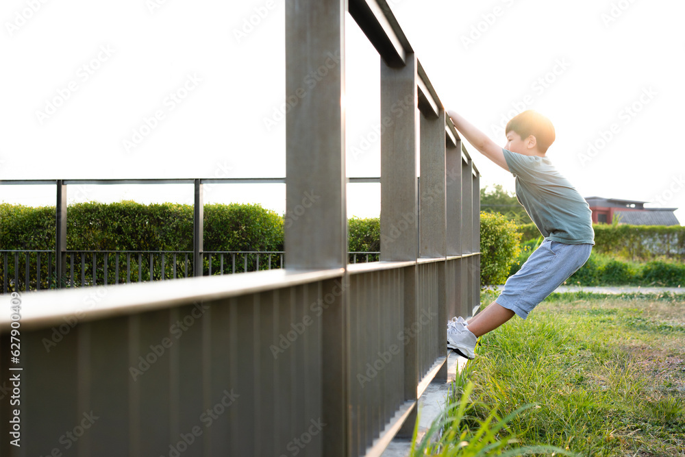 Smart good looking Asian boy stand alone on steel fence, hold on to ...