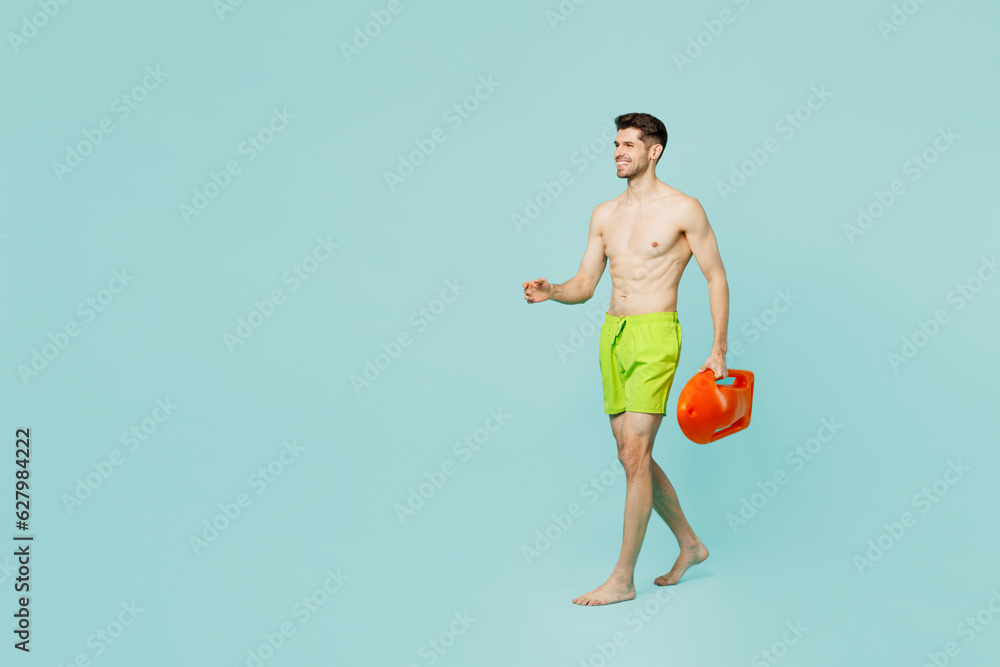 Full body side view young lifeguard man wear green shorts swimsuit ...