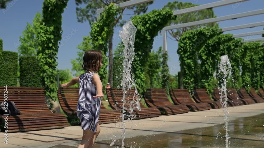 Happy little girl playing with a jet of water. Children play by the ...