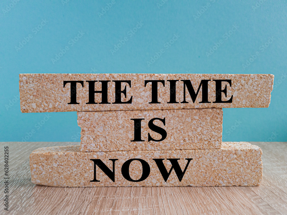 The time is now - words on brick blocks with letters, the time is now ...