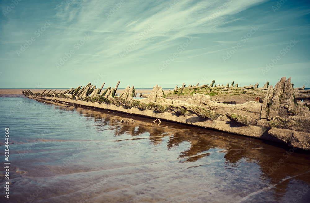 An old historic wooden shipwreck vessel carcass exposed on a desolate ...