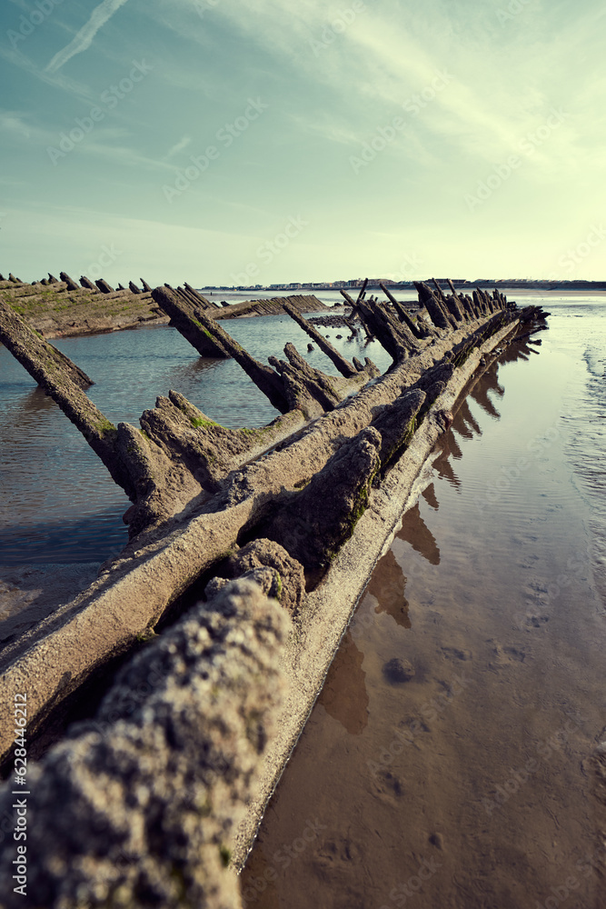 An old historic wooden shipwreck vessel carcass exposed on a desolate ...