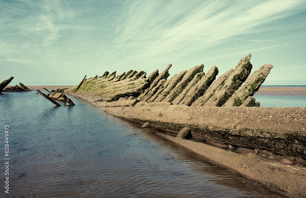 An old historic wooden shipwreck vessel carcass exposed on a desolate ...