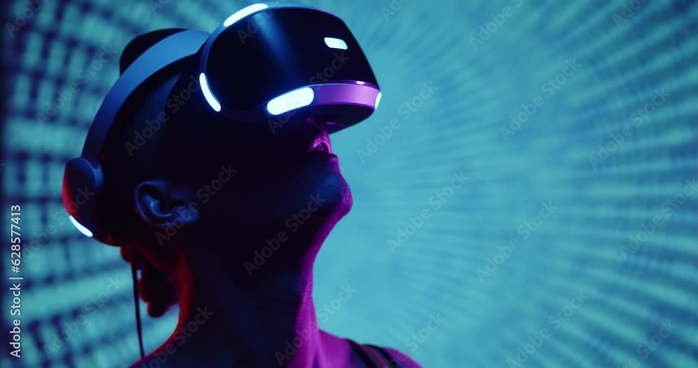 Cyber gamer in VR glasses plays virtual reality game in neon futuristic ...
