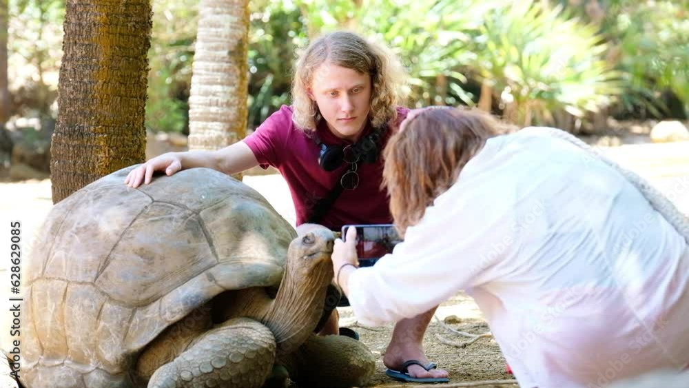 Mother tourist making a photo of son using cell phone with Aldabra ...