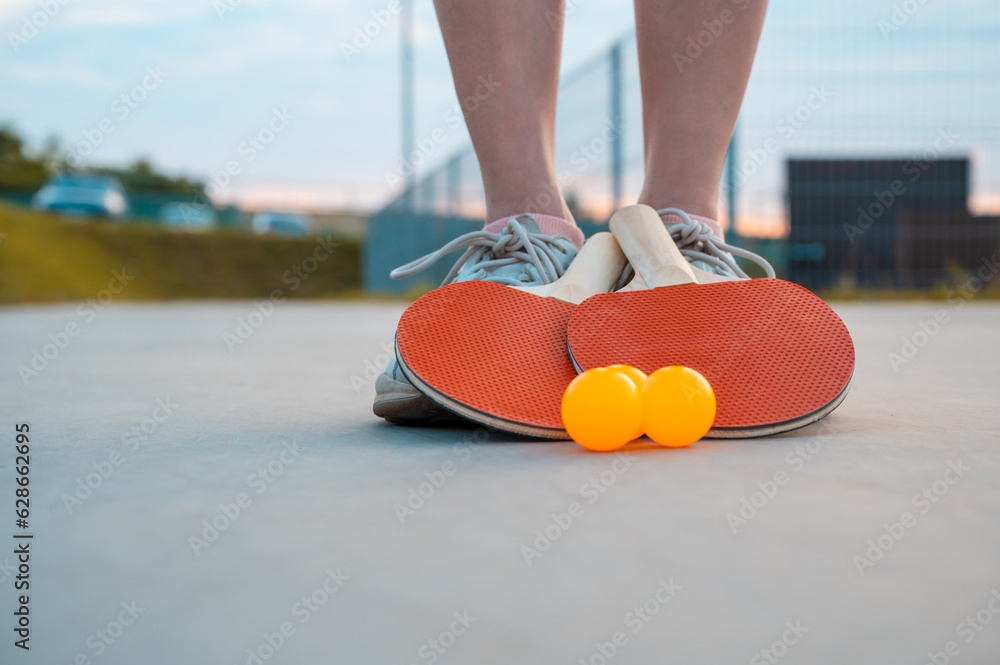 Ping pong paddle and balls on a grey background on woman's feets in ...