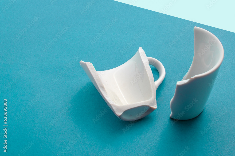 Detail of a broken cup on a blue background, representing vulnerability ...