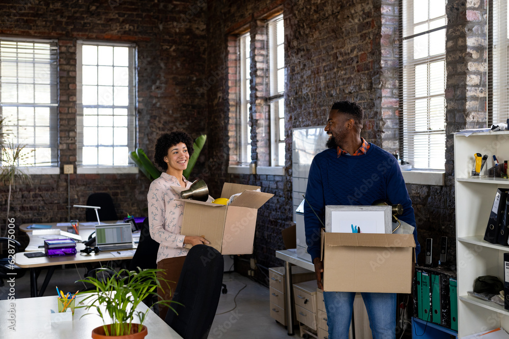 Happy diverse male and female colleagues carrying packing boxes, moving ...