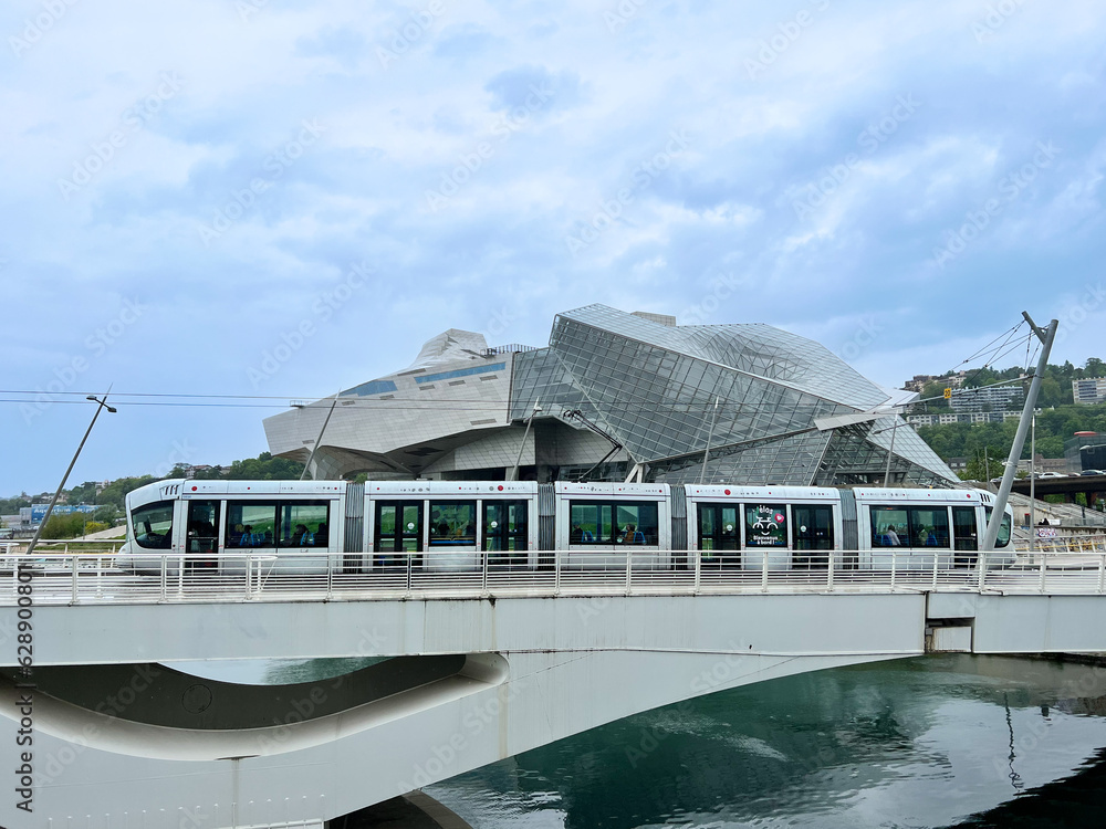 Lyon, France. May 07. 2023. Tram passing over the pedestrian bridge ...