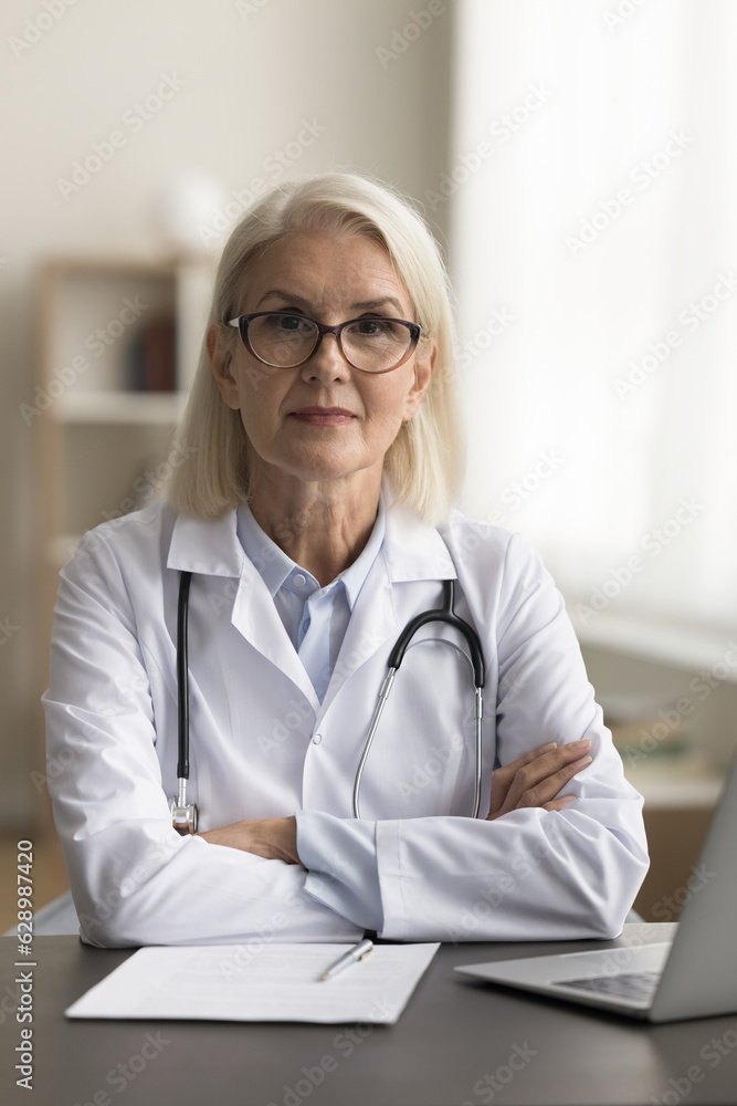 Confident mature practitioner woman in glasses posing with crossed ...