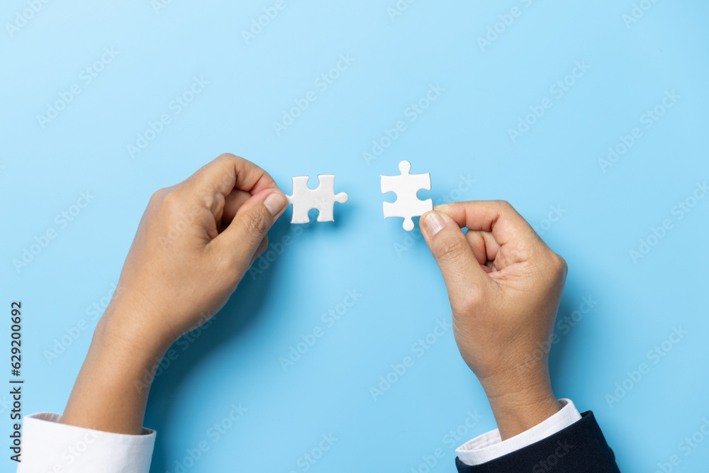 Two hands trying to connect couple puzzle piece on blue background ...