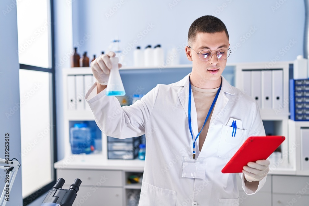 Young hispanic man scientist measuring liquid using touchpad at ...