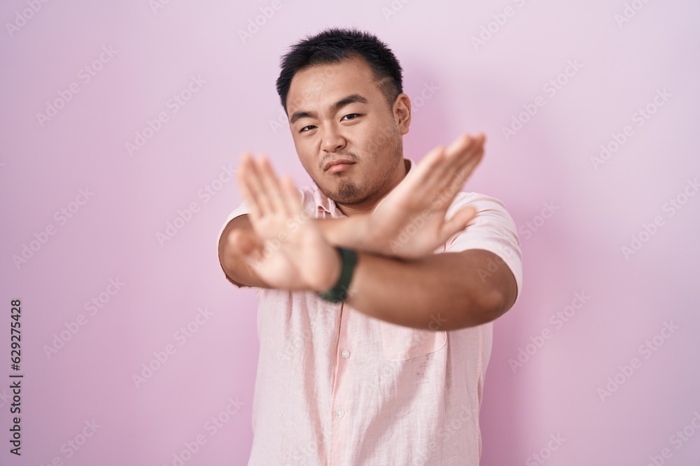 Chinese young man standing over pink background rejection expression ...