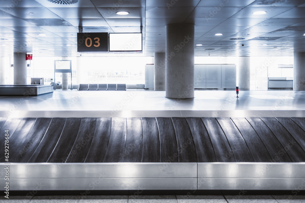 A wide-angle indoor view of a modern baggage reclaim area with an empty ...