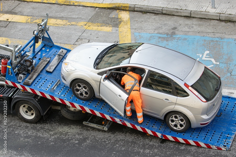 Roadside assistance concept. Damaged car being loaded onto tow truck by ...