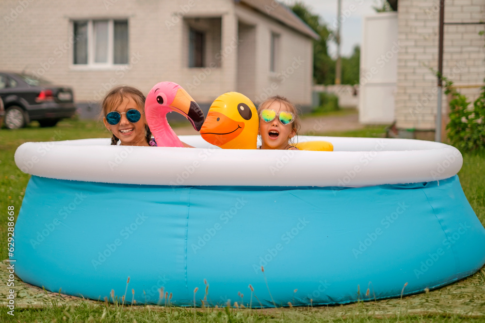 Funny humorous girls look out of a small inflatable swimming pool in ...