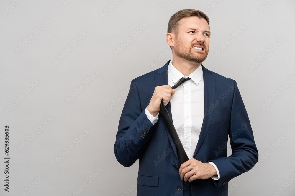 Nervous businessman putting off tie wearing in official blue suit with ...