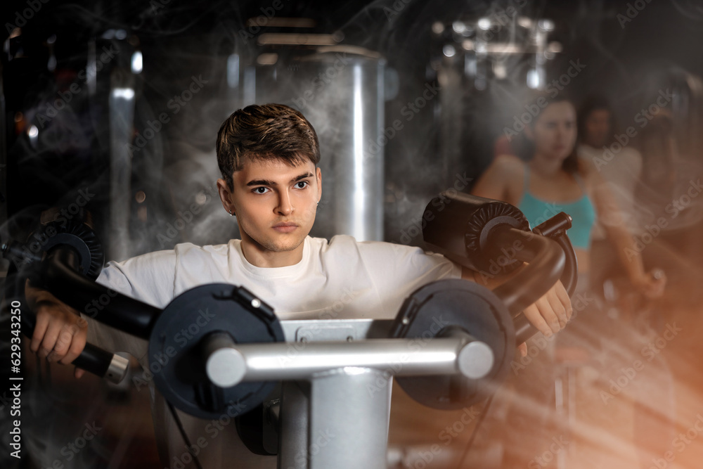 Foto de Focused young guy working out in modern gym, pumping up deltoid ...
