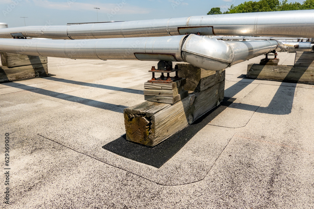 Roof mounted industrial insulated HVAC pipes on gray roof and wooden ...