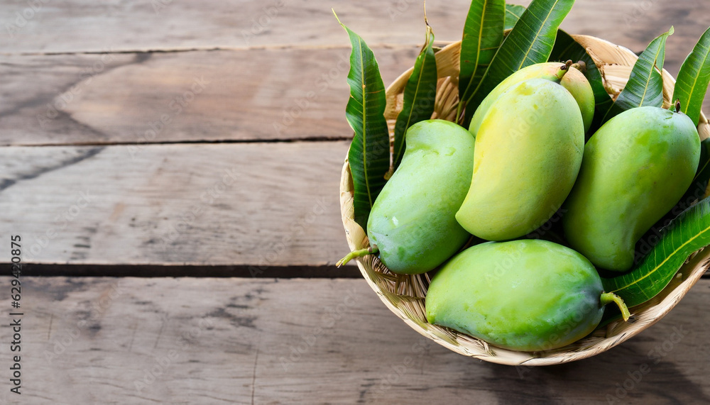 Green mango and green leaf on basket and old wooden floor background ...