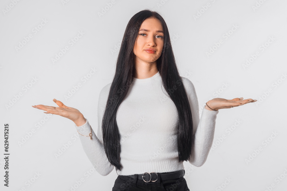 What's wrong. Confused beautiful woman spreads hands sideways, smirks ...