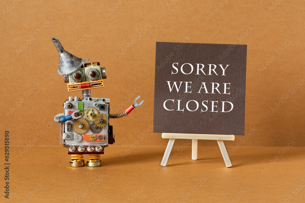 Sorry we are closed. A robot stands next to an easel and a brown poster ...