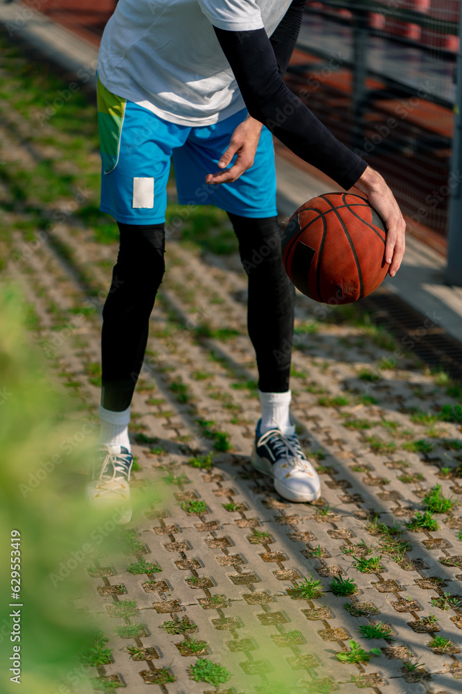A tall guy basketball player walks down the park path to the basketball ...