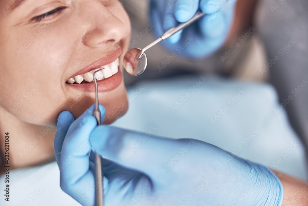 Confident mature doctor is checking teeth of young beautiful happy ...