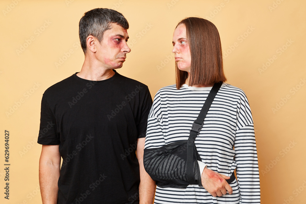 offended sad man and woman with bruise isolated over beige background ...
