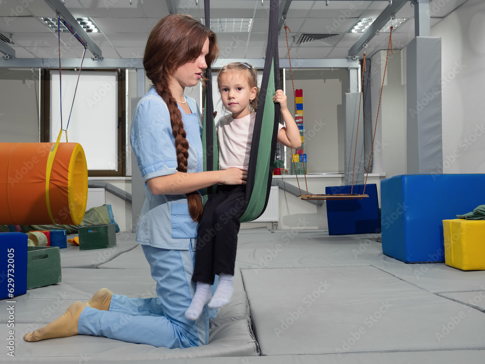 Child with physiotherapist on swing during sensory integration session ...