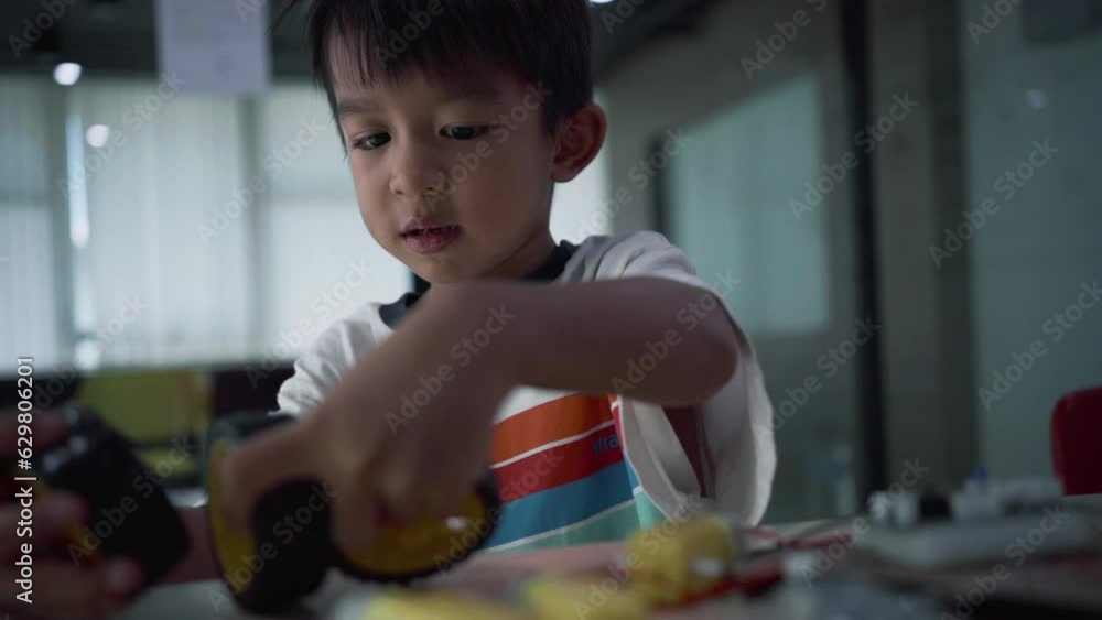 Little kindergarten asian boy constructing arduino robot arm project in ...