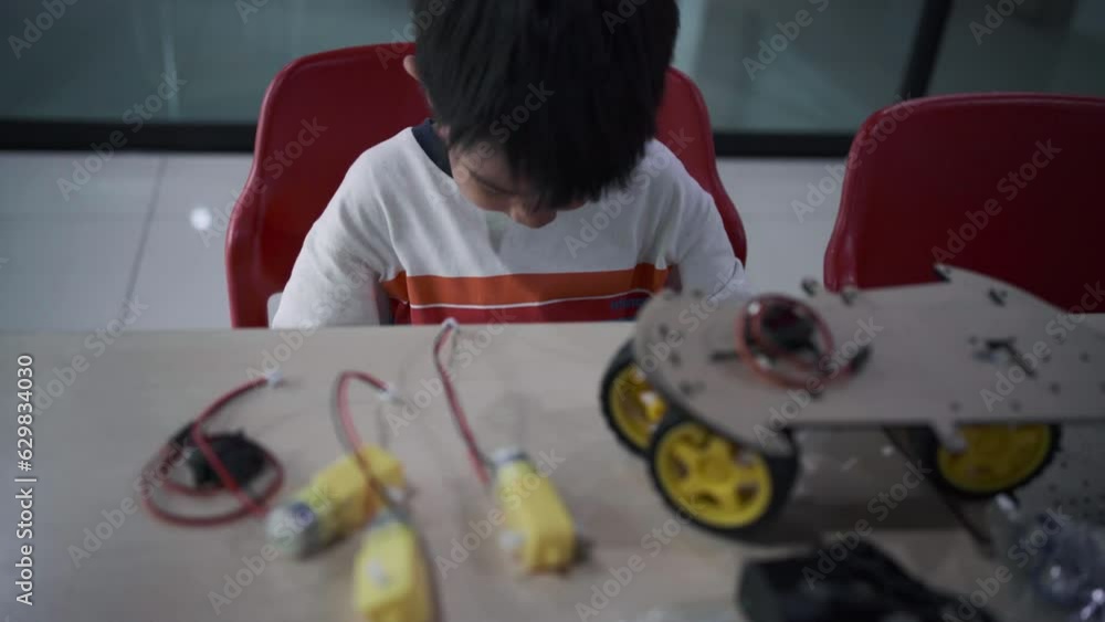 Little kindergarten asian boy constructing arduino robot arm project in ...