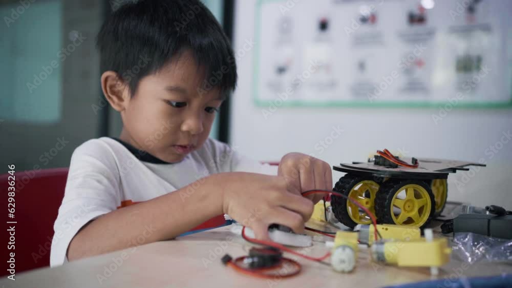 Little kindergarten asian boy constructing arduino robot arm project in house. technology of ...