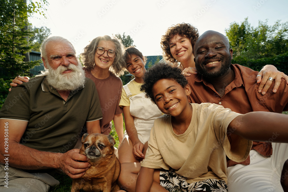 Happy intercultural family of three generations sitting on green lawn ...