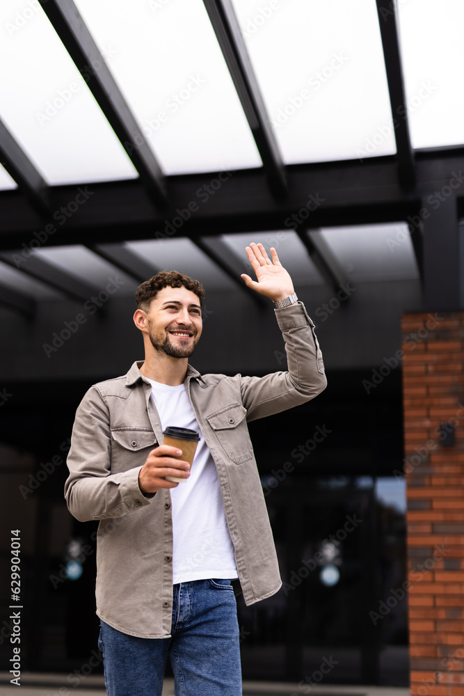 Attractive man standing outside waving hand, saying goodbye to his ...