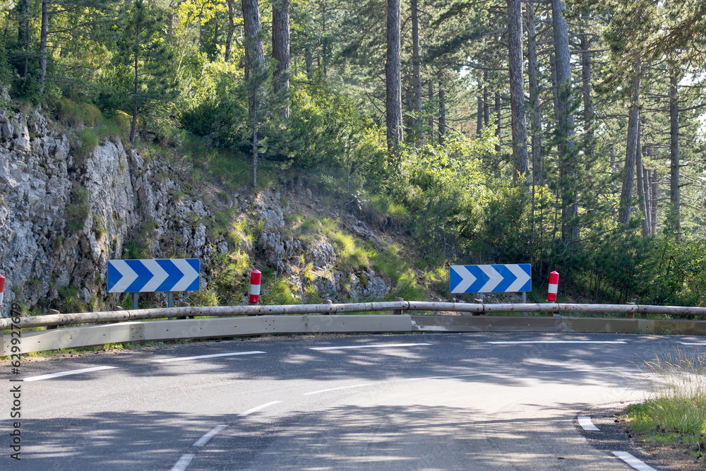 virage dangereux avec signalétique sur une route de forêt en montagne ...