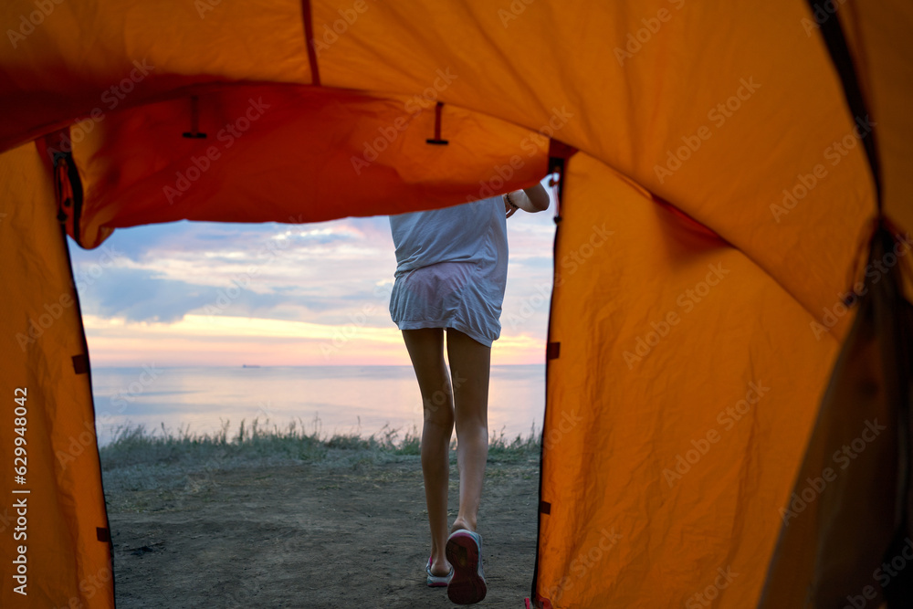 Woman stepping out of her tent into a breathtaking sunrise landscape ...