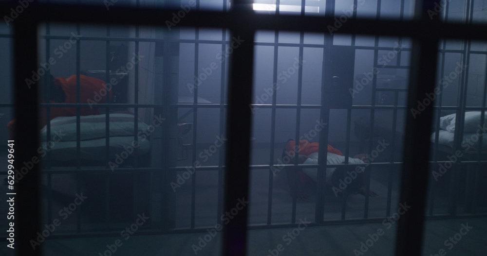 African American prisoner in orange uniform does push-ups and shadow ...