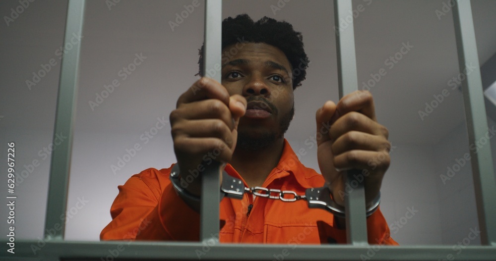 Foto de African American prisoner in orange uniform keeps hands in ...