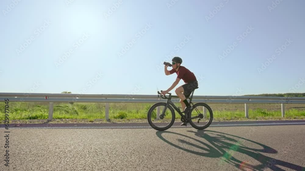 Side view of professional cyclist drinking from sports bottle while ...