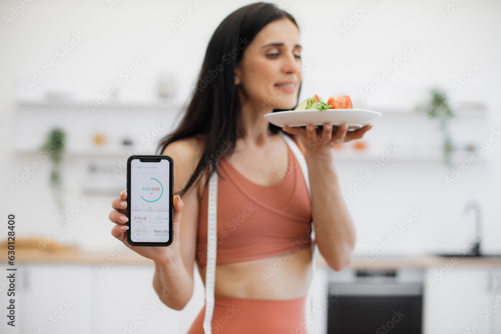 Yong caucasian woman using calorie counting app on smartphone for ...