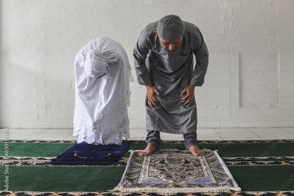 Front view of muslim couple wearing praying salah together in mosque ...