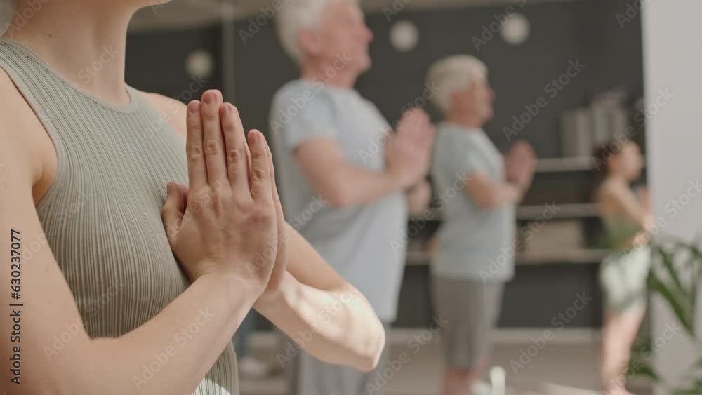 Tilt up cropped shot of young slim woman in sports outfit raising arms ...