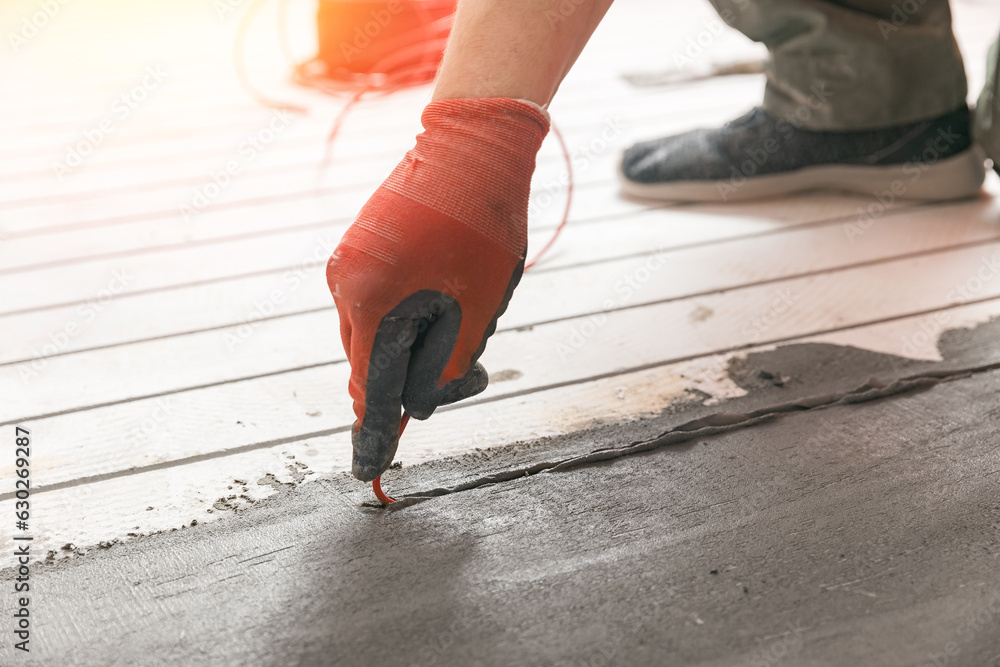 Master builder install red electric cable in concrete floor for heating ...
