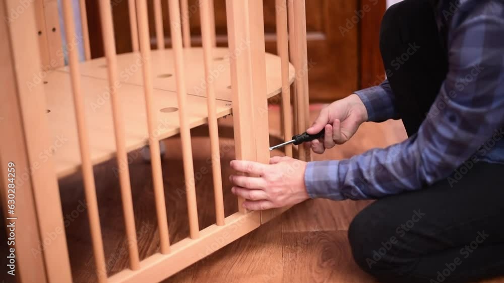 Man fixing wooden crib bed, preparation for the appearance of a newborn ...