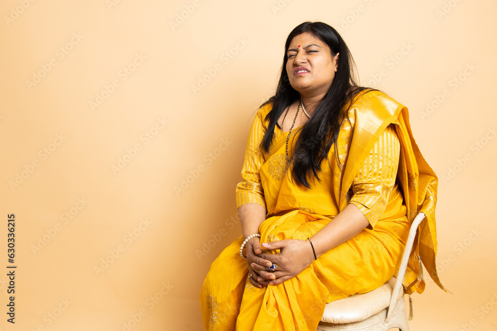 Indian woman wearing yellow saree feeling knee pain sitting on chair ...