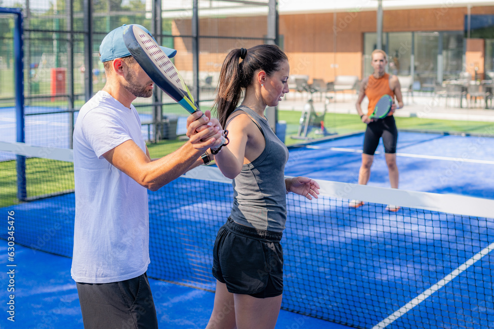 Game of padel outdoor lesson, coach instructs a young woman, fostering ...
