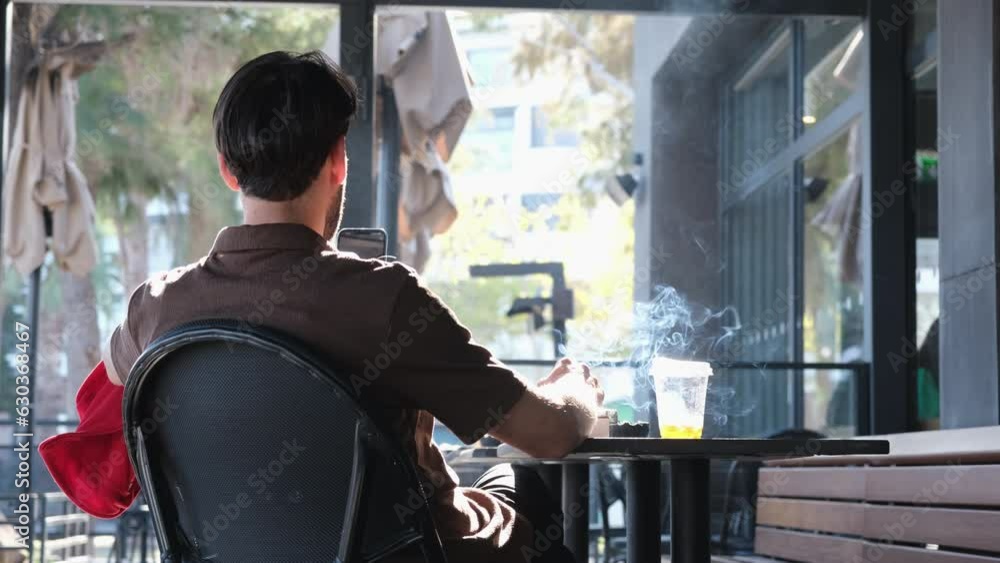 Back view of young man smoking tobacco cigarette in cafe. Unhealthy ...