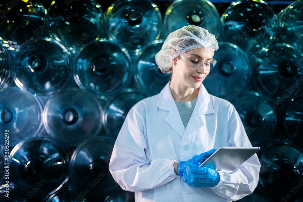 woman worker in a drinking water factory in a professional uniform ...